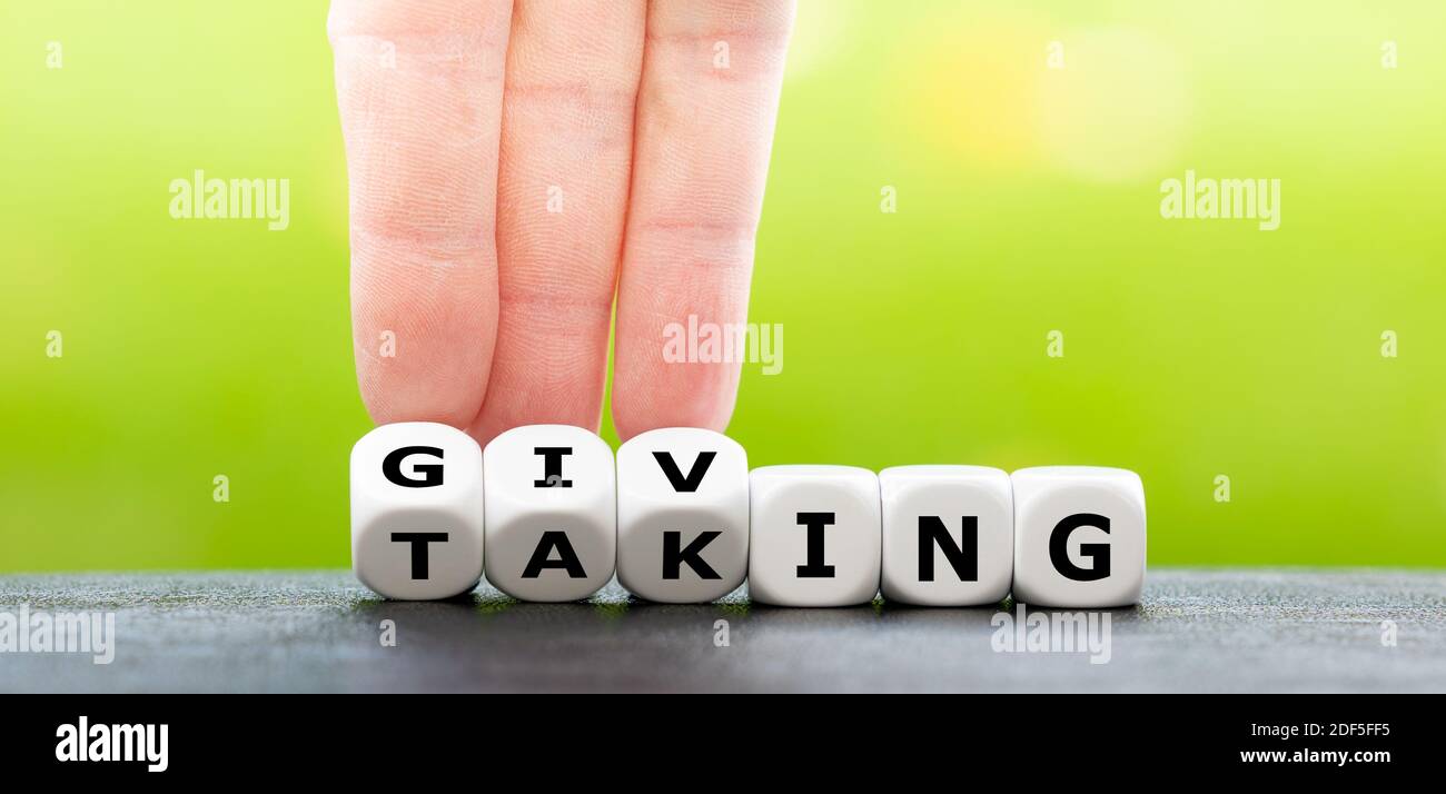 Hand turns dice and changes the word taking to giving Stock Photo - Alamy