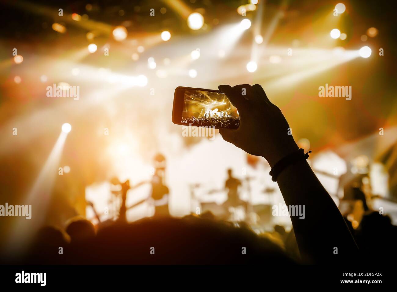 Filming a concert on mobile phone camera, yellow light of stage Stock ...