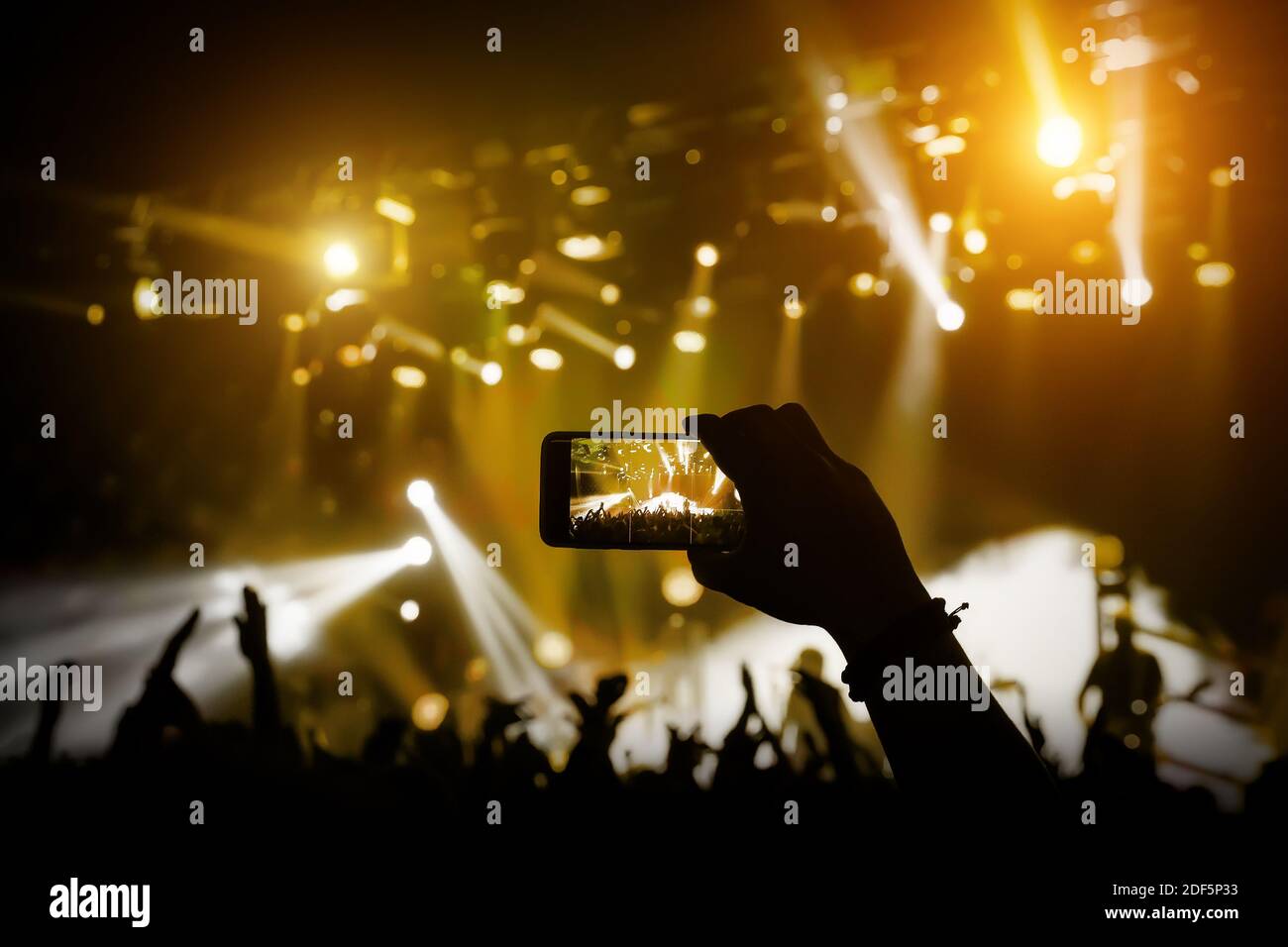 Filming a concert on mobile phone camera, yellow light of stage Stock ...
