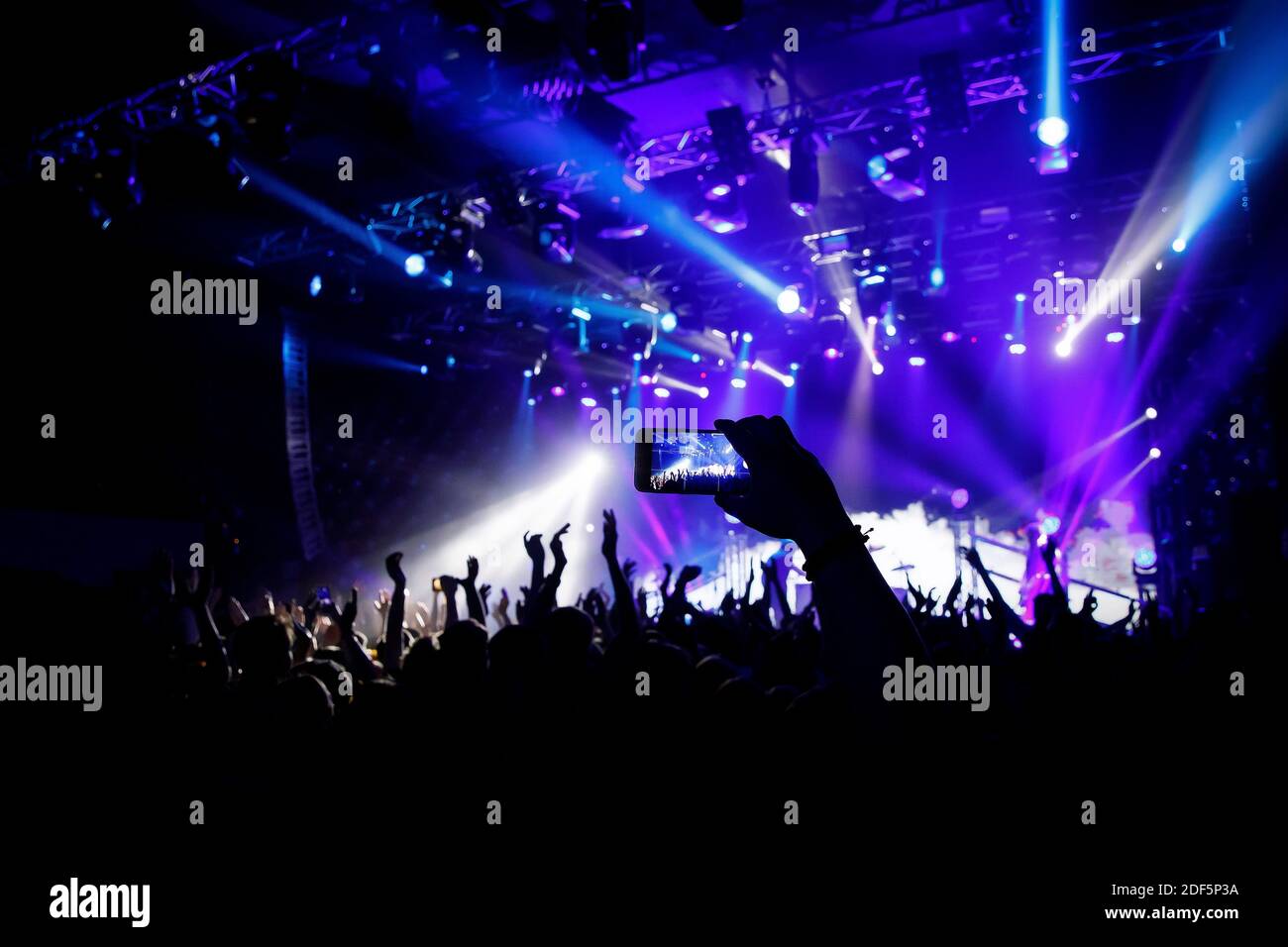 Filming a concert on mobile phone camera, blue light of stage Stock ...