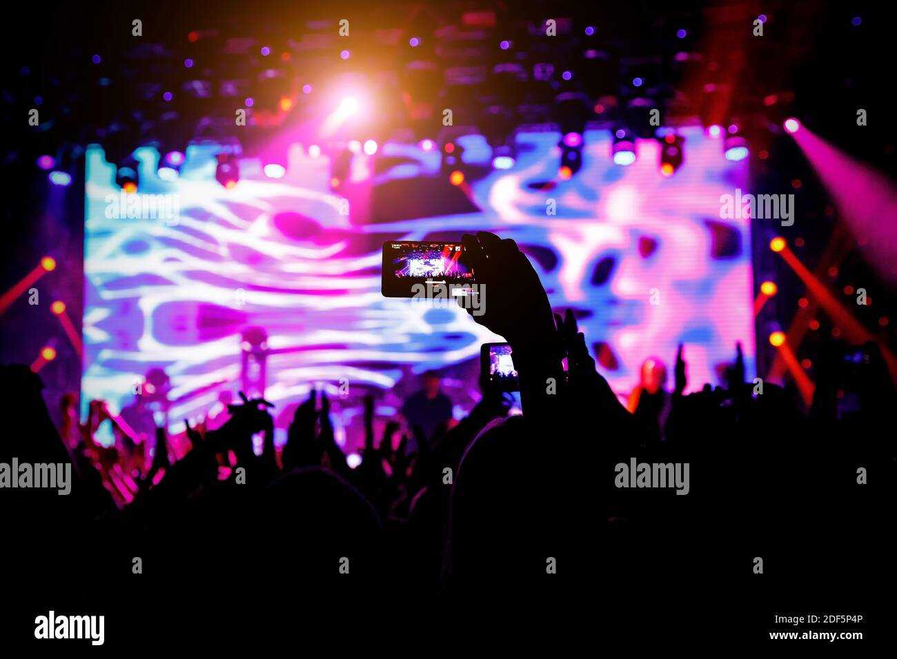 Smartphone in hand at a concert, purple light from stage Stock Photo ...