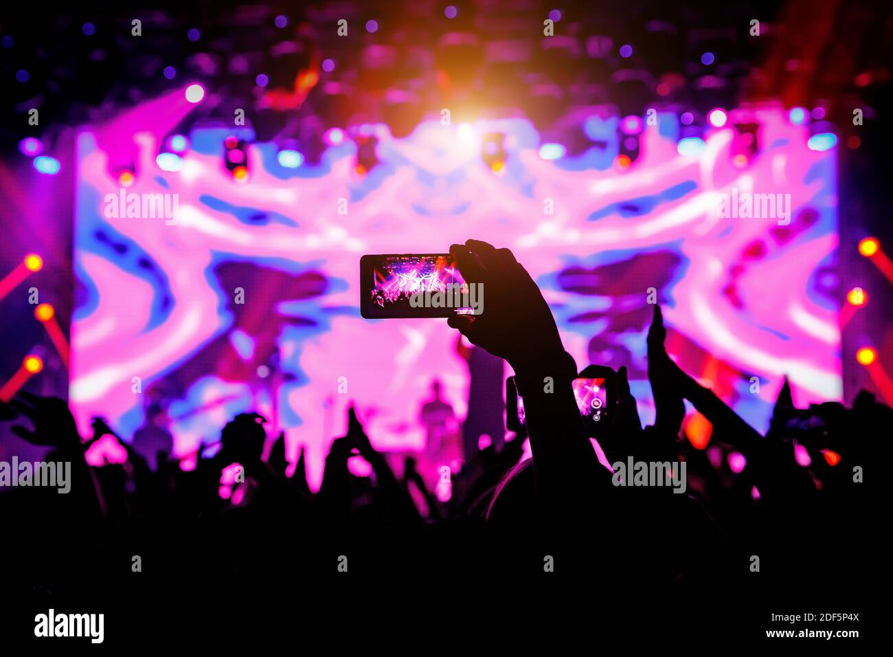 Smartphone in hand at a concert, purple light from stage Stock Photo ...