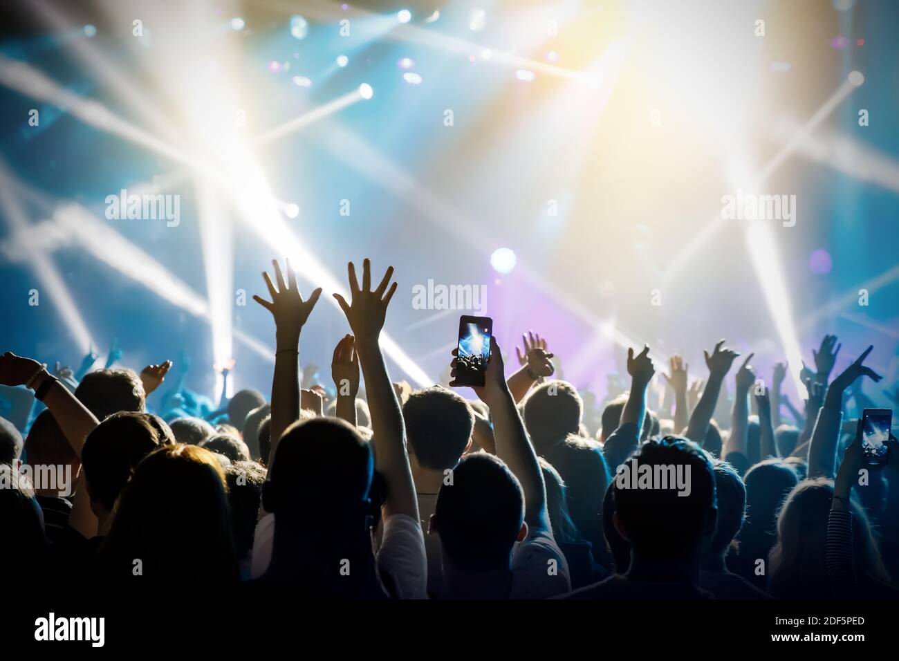 Raised hands in honor of a musical show on stage, People in the hall ...