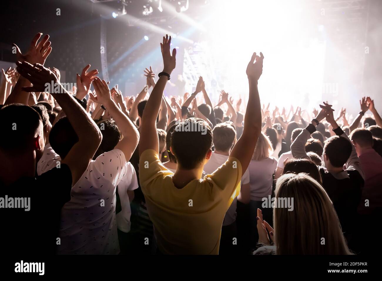 Raised hands in honor of a musical show on stage, People in the hall ...