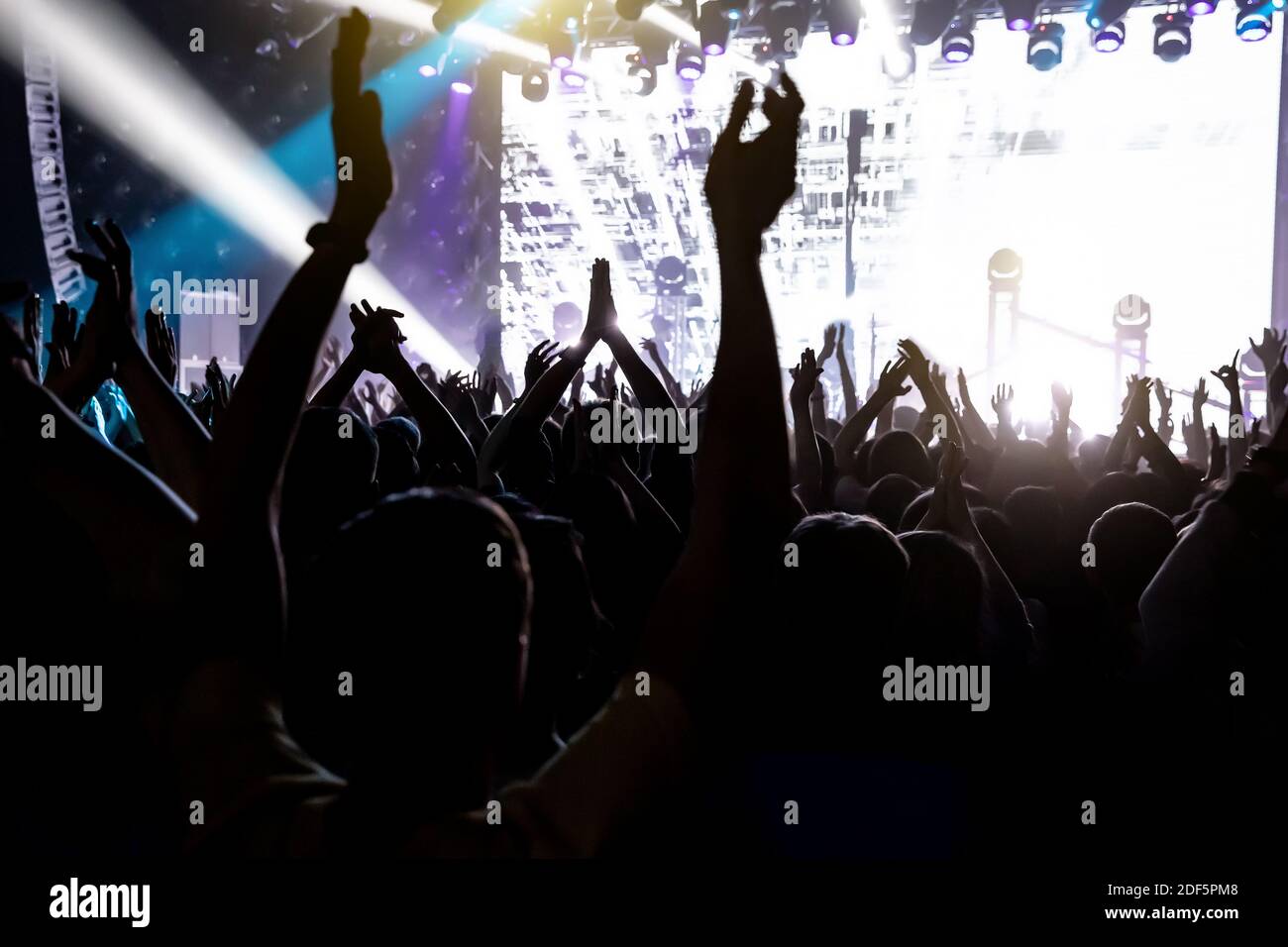Raised hands in honor of a musical show on stage, People in the hall ...