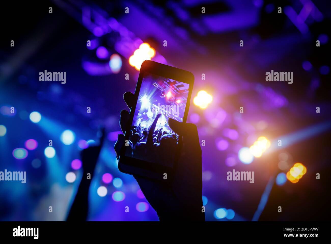 Filming a concert on mobile phone camera, blue light of stage Stock ...