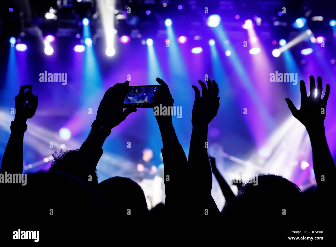 Filming a concert on mobile phone camera, blue light of stage Stock ...