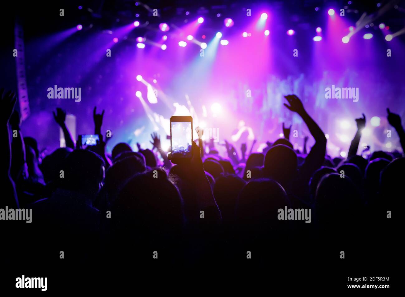 Smartphone in hand at a concert, purple light from stage Stock Photo ...