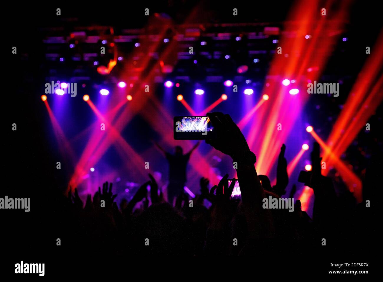Smartphone in hand at a concert, purple light from stage Stock Photo ...