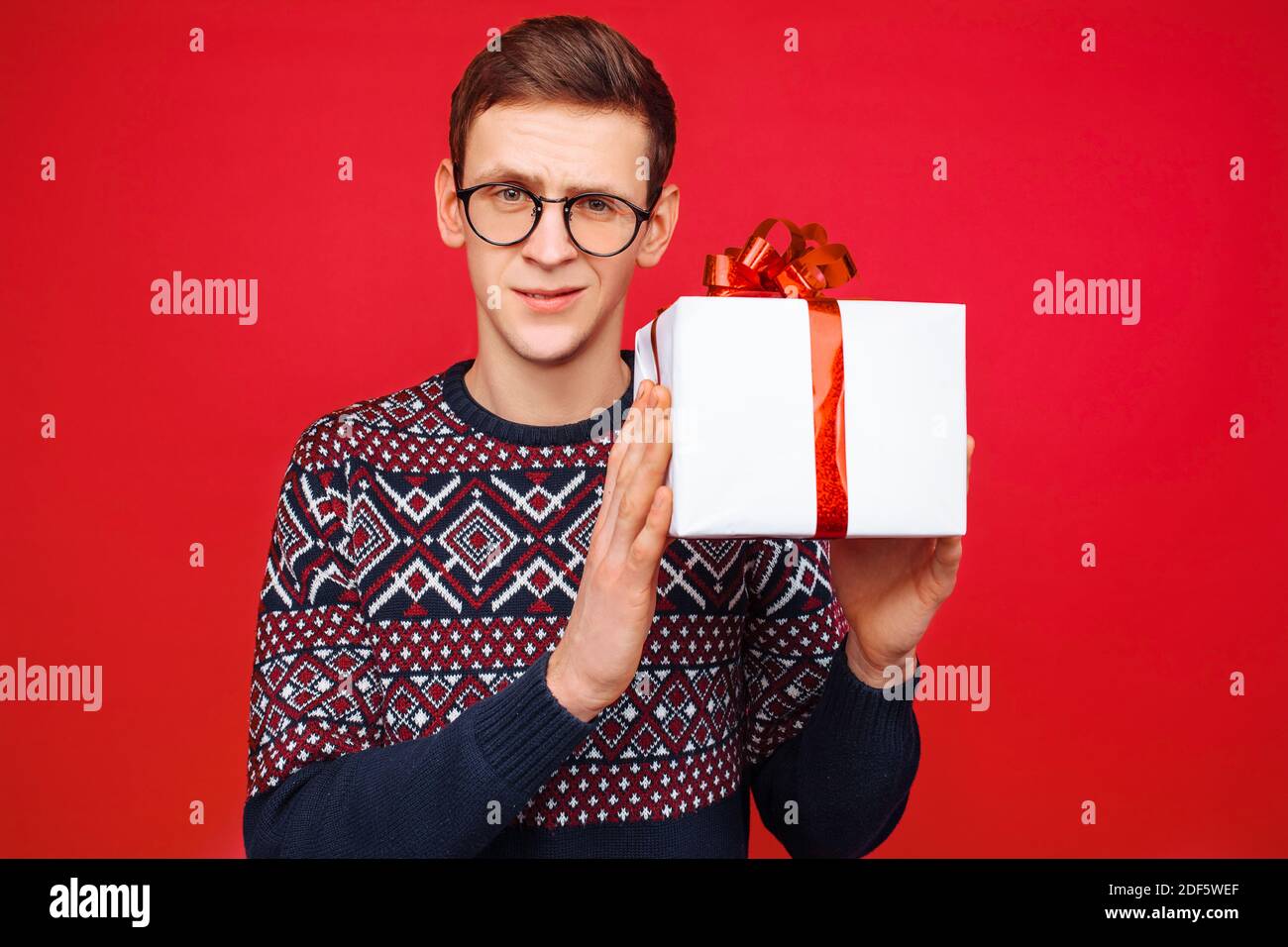 Curious man with glasses, a man holding a gift box, shaking it to find ...