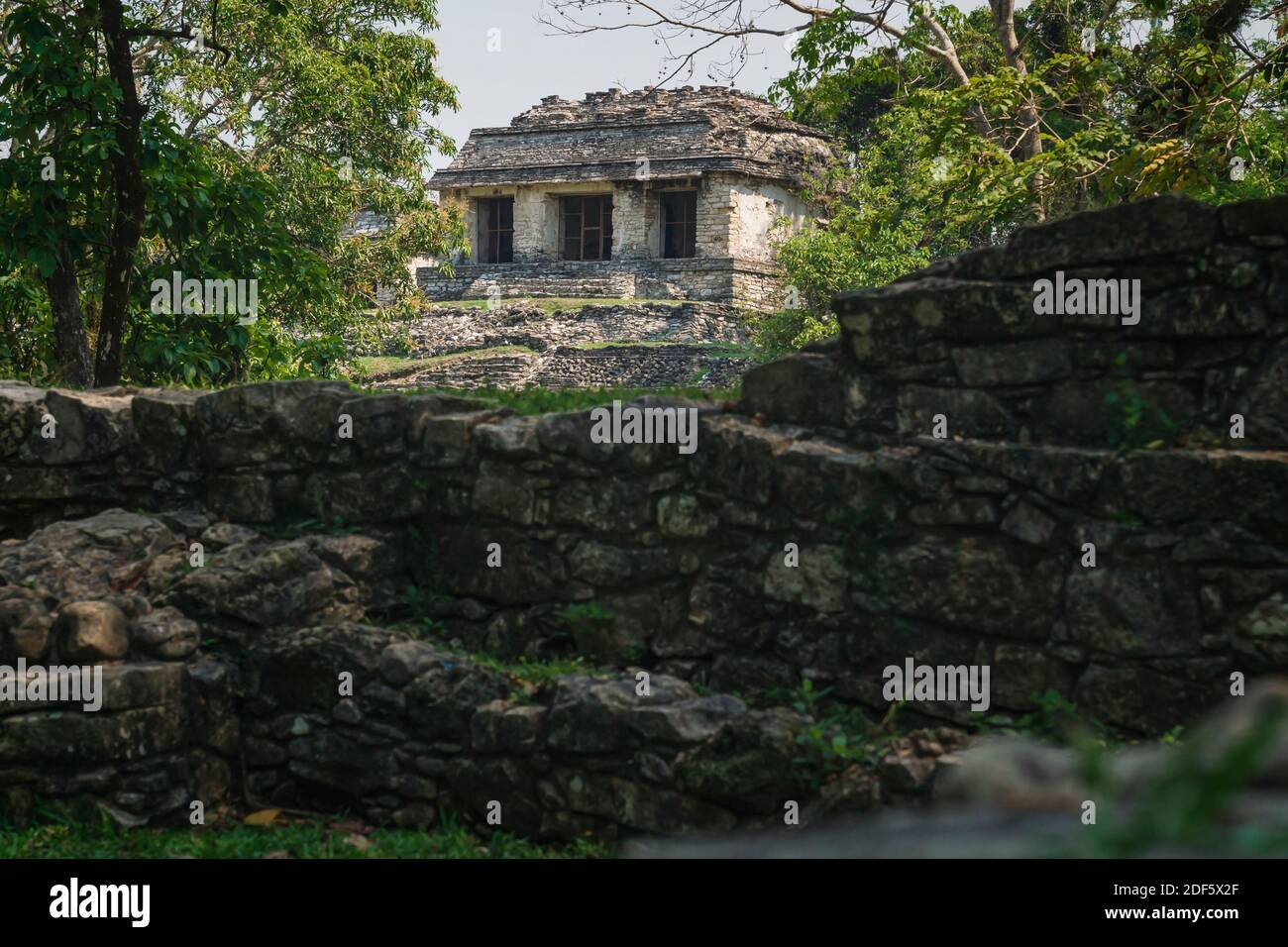 Small pyramid Mayan temple behind ruin walls at the archaeological site ...