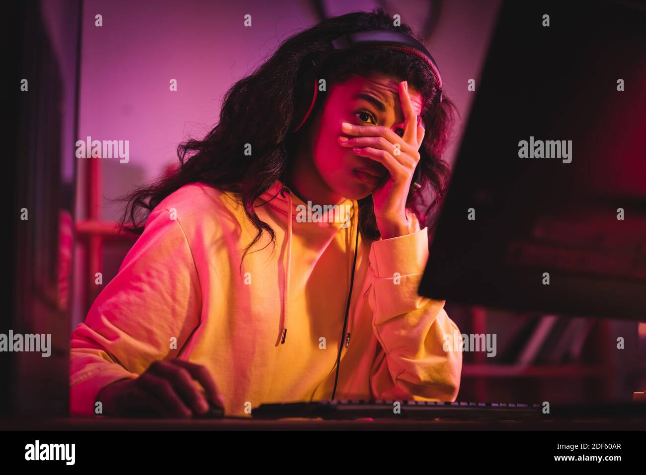 Exhausted african american gamer in headset using computer during video ...