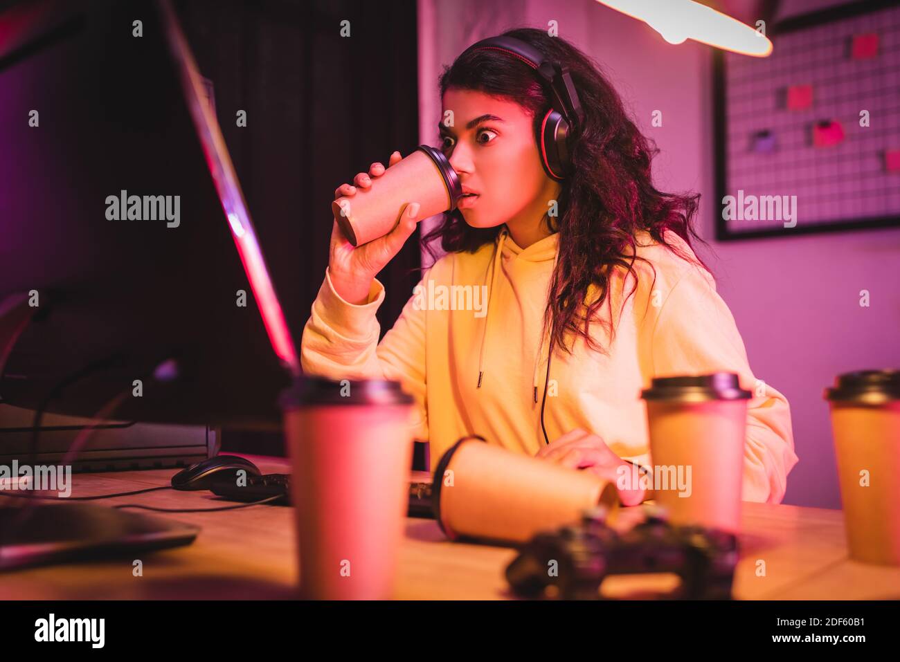 Excited african american gamer in headset drinking coffee to ho near ...