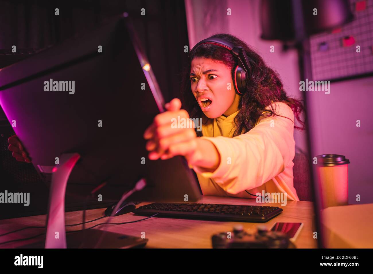 Crazy african american gamer in headset holding computer monitor near ...