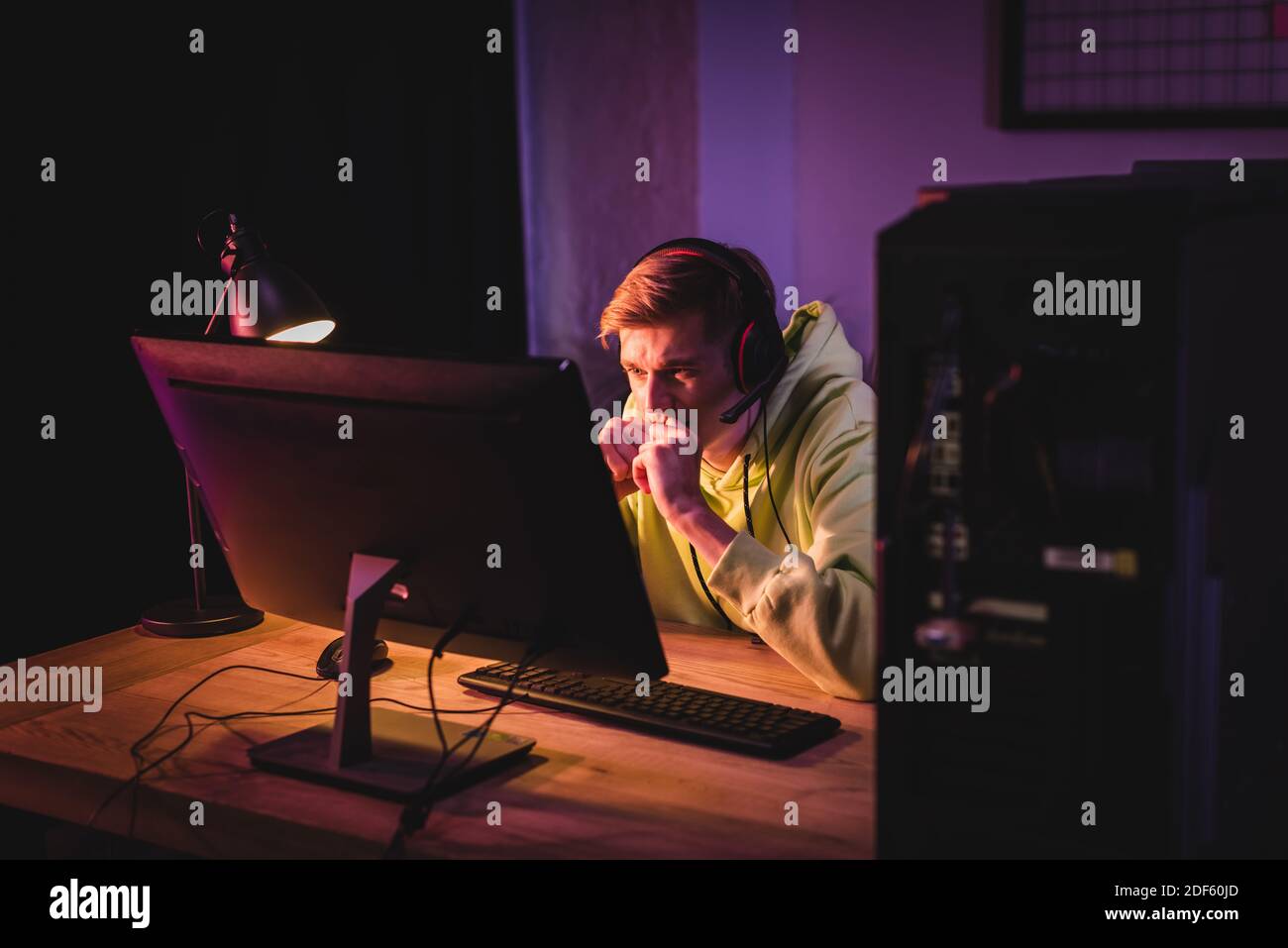 Tensed gamer in headset looking at computer monitor during video game ...