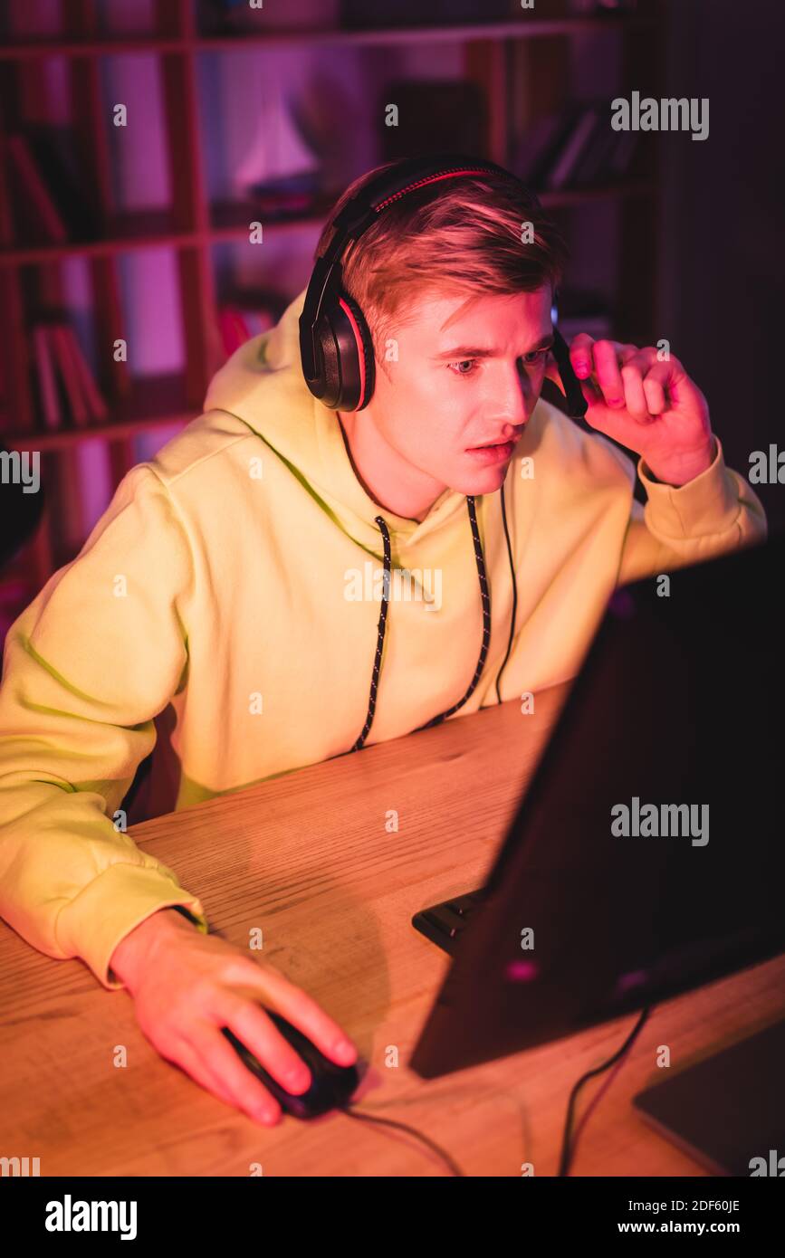 Young man using headset while gaming on computer on blurred foreground ...