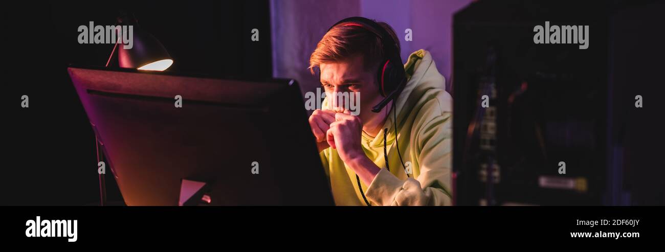 Stressed gamer in headset looking at computer monitor near system unit ...