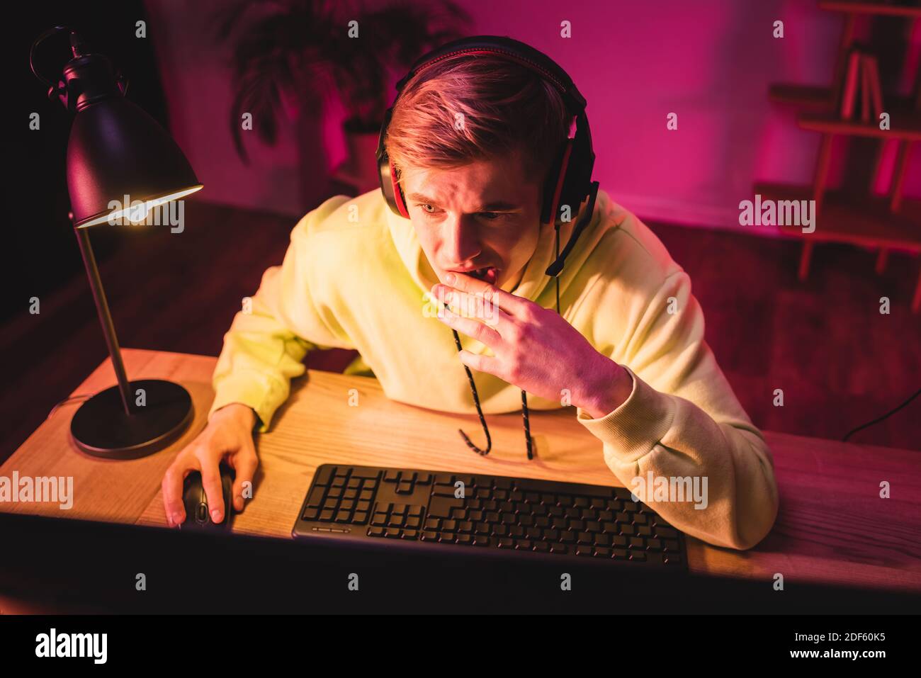 Nervous gamer in headset using computer on blurred foreground Stock ...