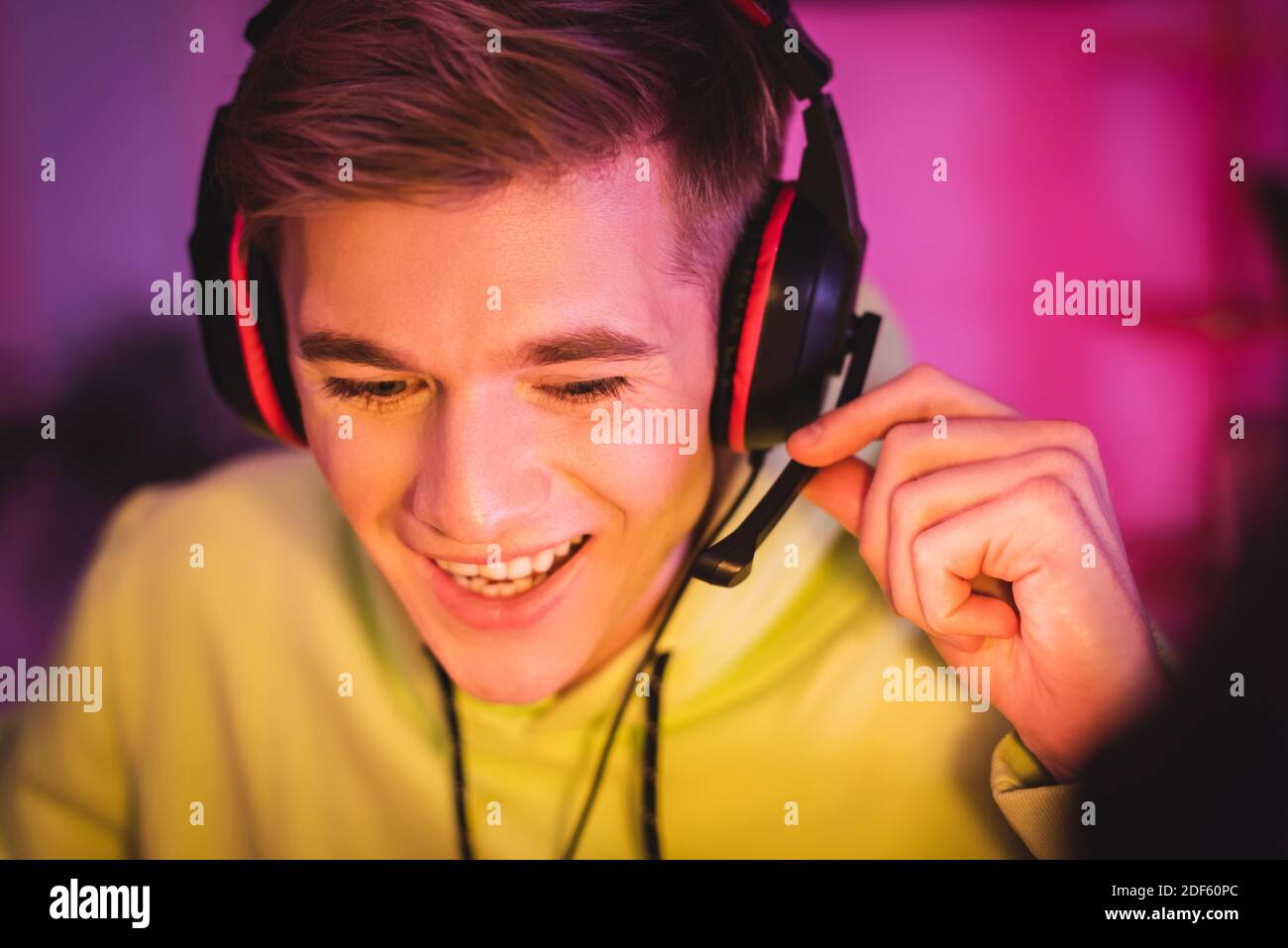 Cheerful gamer adjusting microphone of headset at home Stock Photo - Alamy