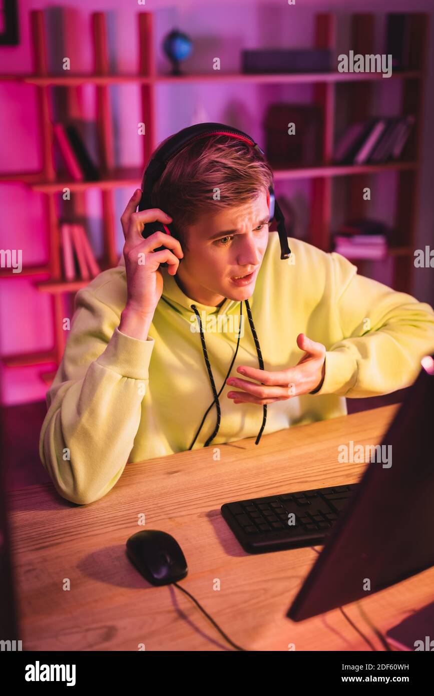 Player using headset while talking during video game near computer on ...