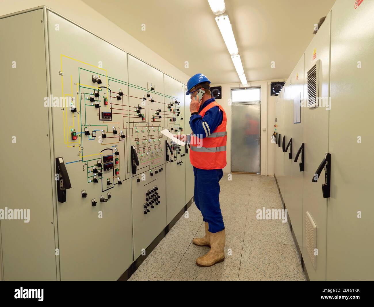 Worker stay in large control room. Power Plant Control Panels with ...
