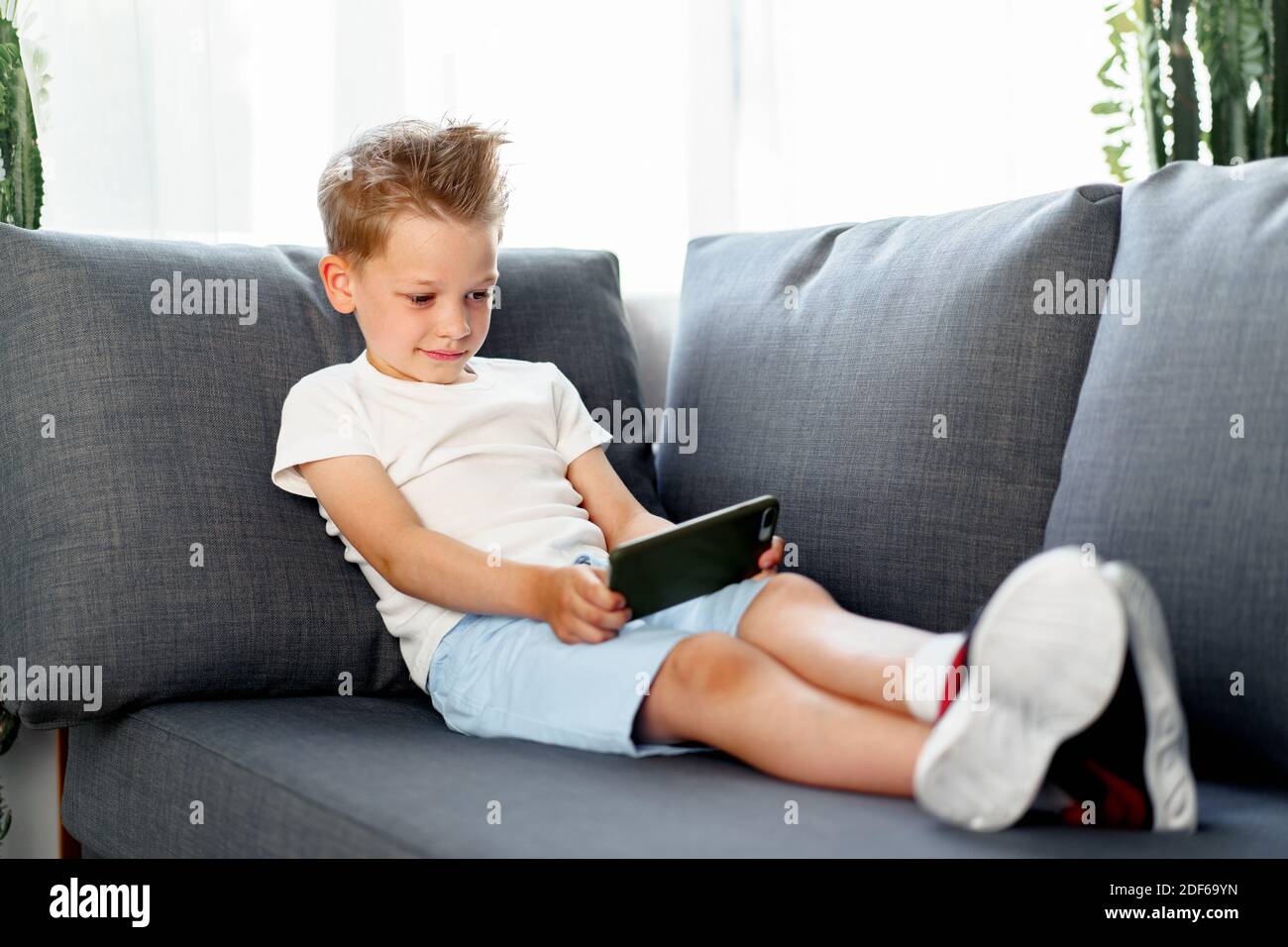 Little boy using smartphone while lying on sofa at home Stock Photo - Alamy