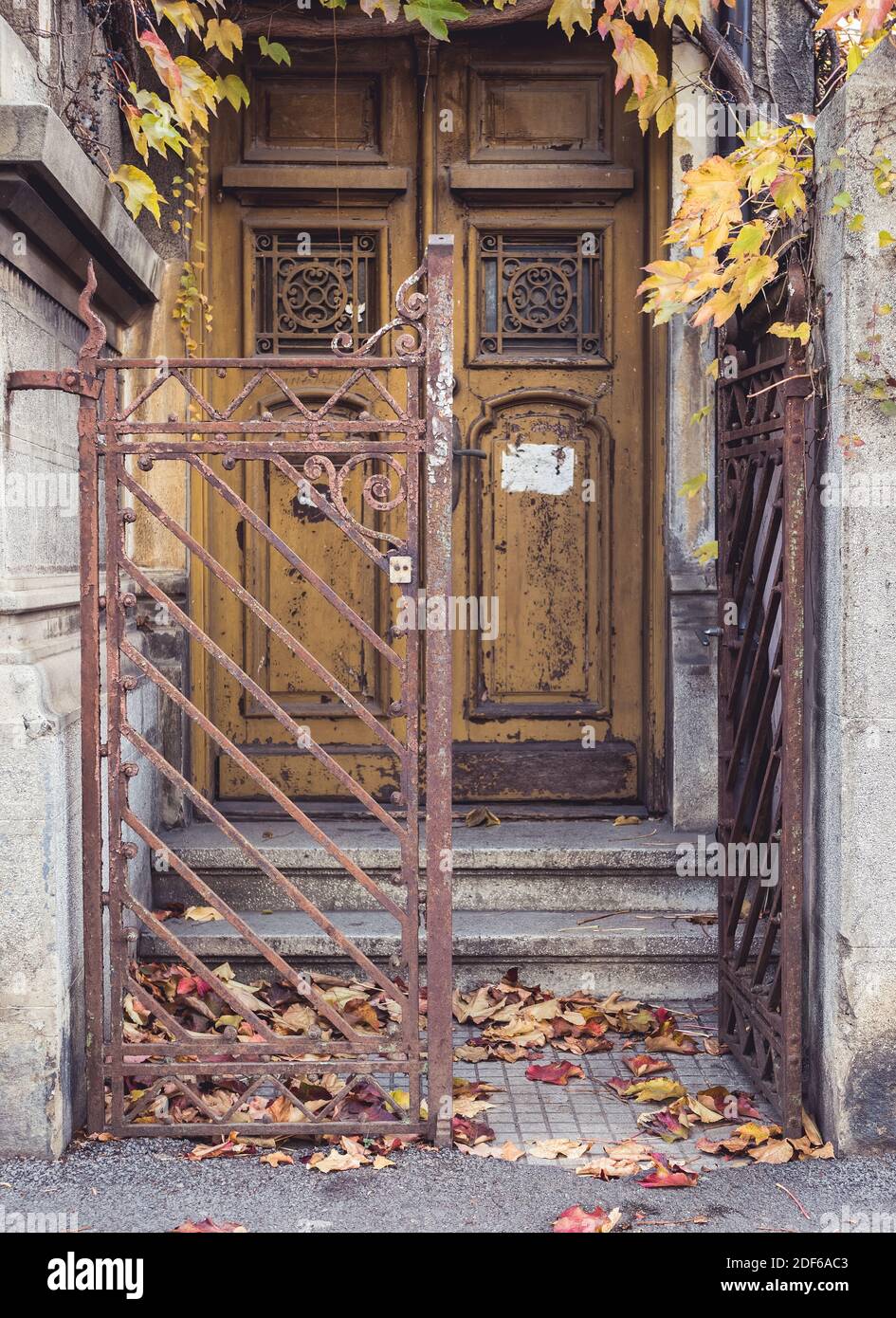 The entrance to an old house with a rusty gate and a worn out door ...