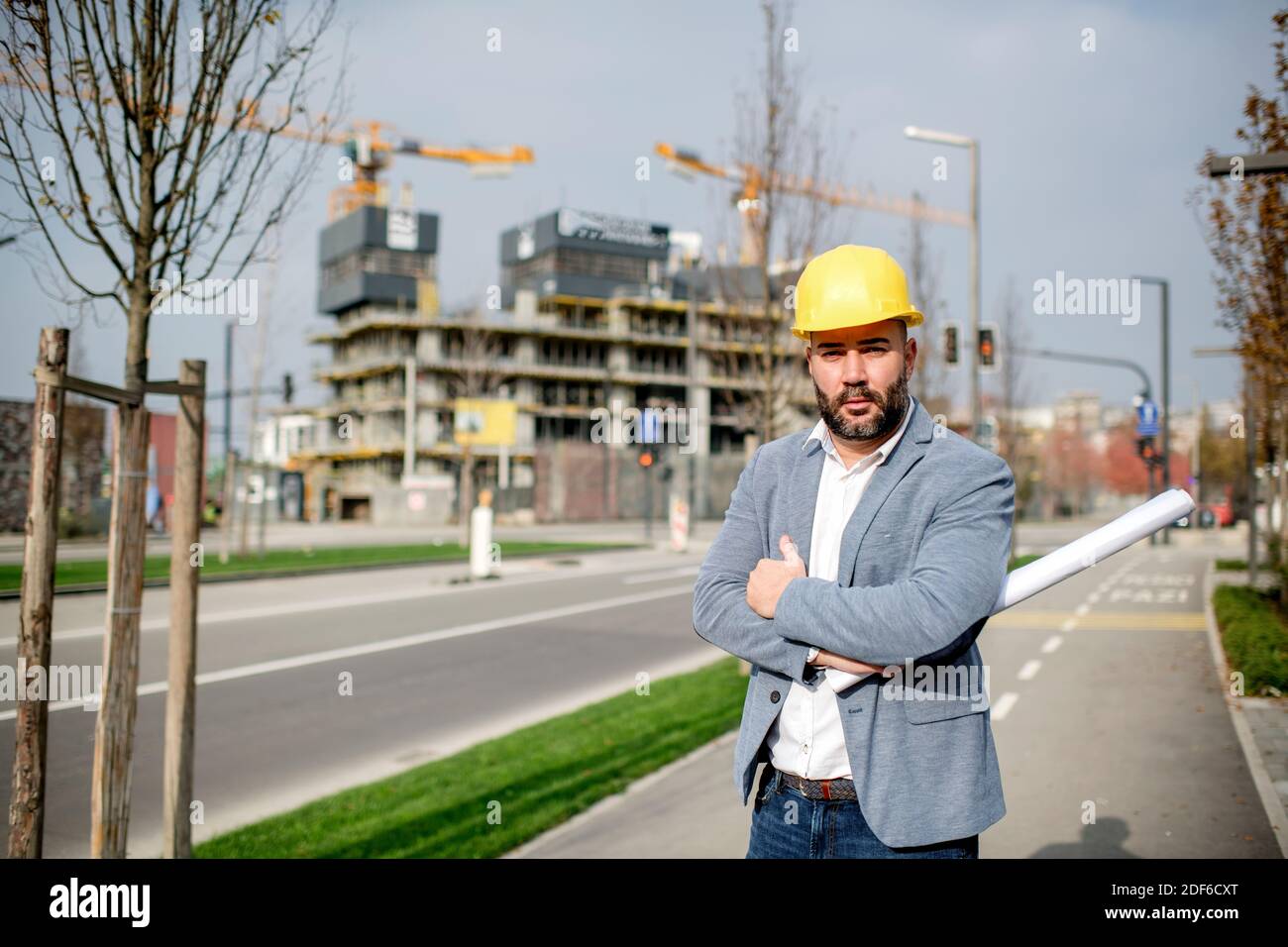 Portrait of bearded architect holding project while standing on ...