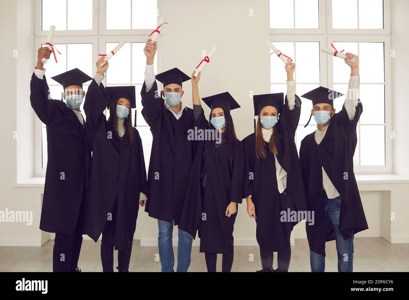 University graduates in protective medical face masks standing and ...