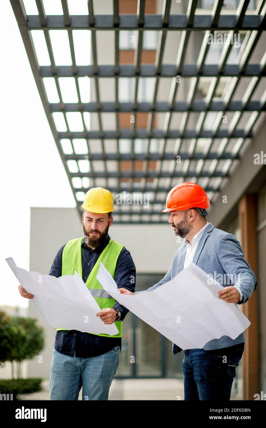 Two architects examining a blueprint and working on a building project ...