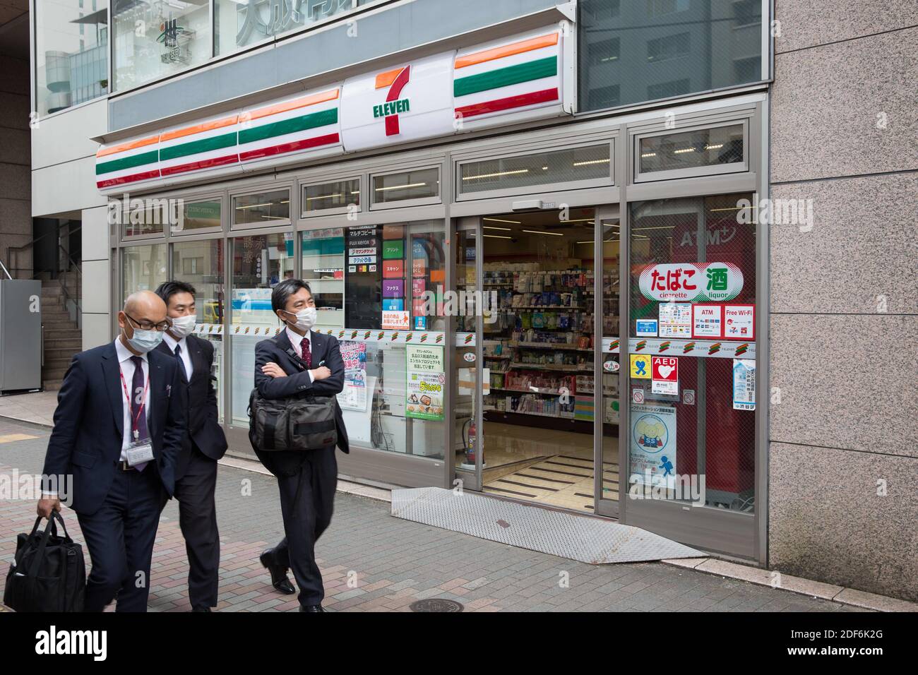 Tokyo, Japan. 30th Oct, 2020. Japanese business men walk past a Seven eleven (7/11) store in ...