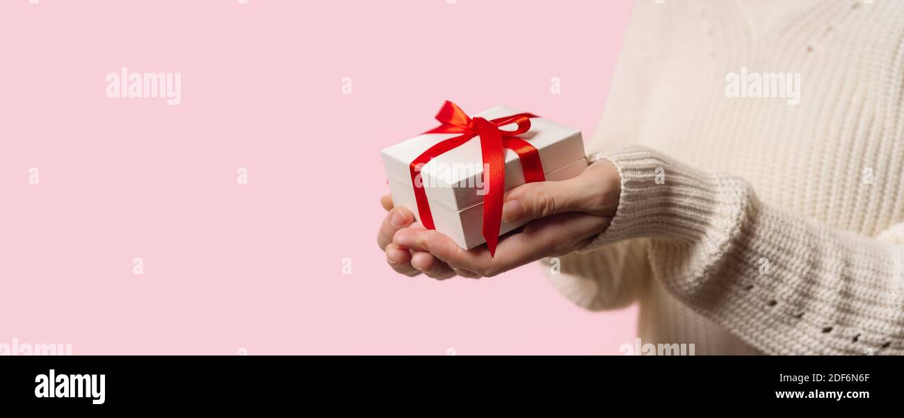 Woman hands holding Gift box with red bow on pink background Stock ...