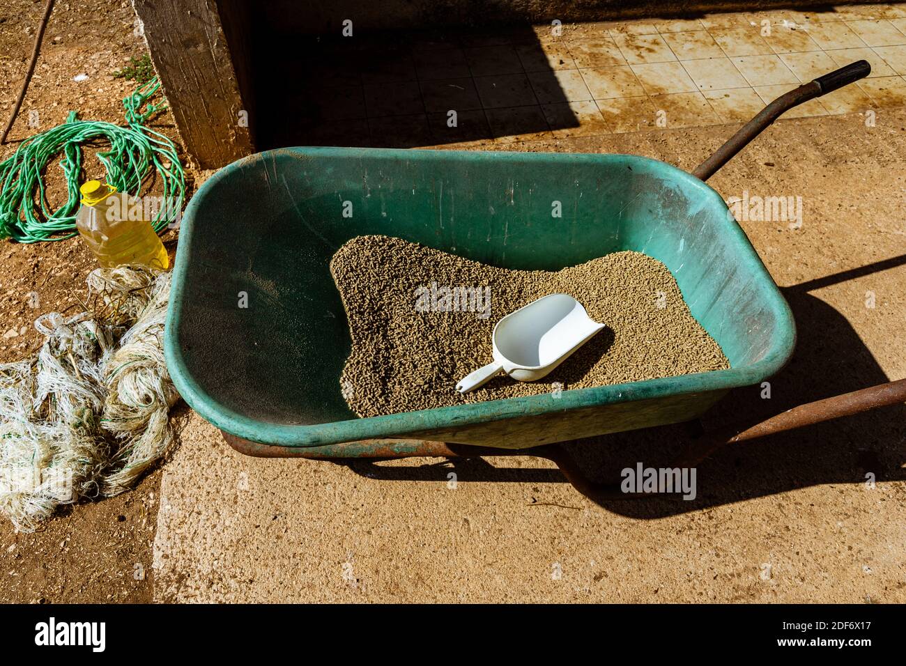 A shot of an old barrow with building material in it and a white shovel ...