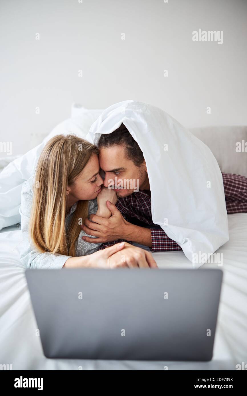 Happy loving couple cuddling and using laptop at home Stock Photo - Alamy