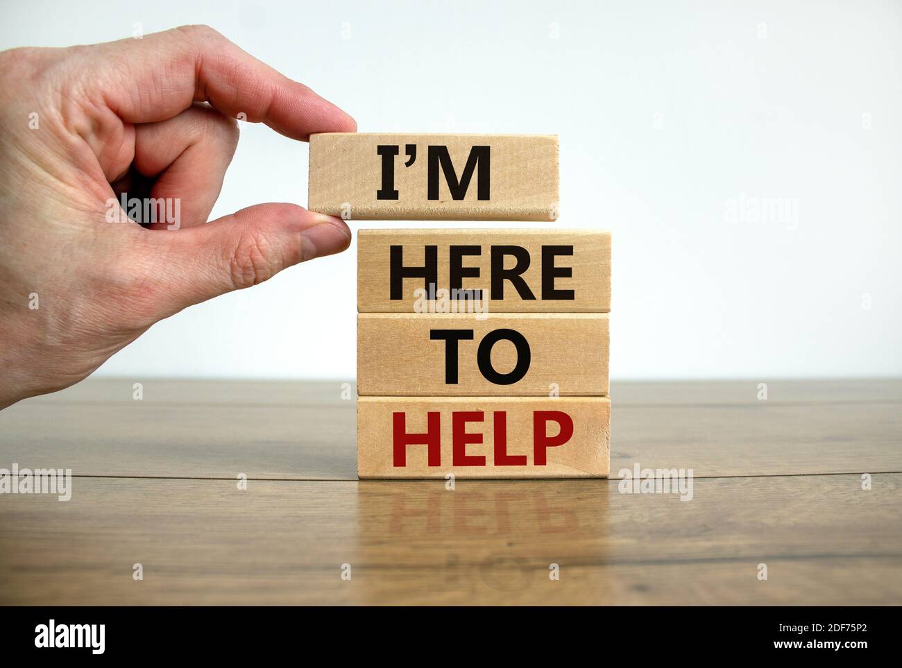 Here to help symbol. Male hand builds stack from blocks with words 'i ...