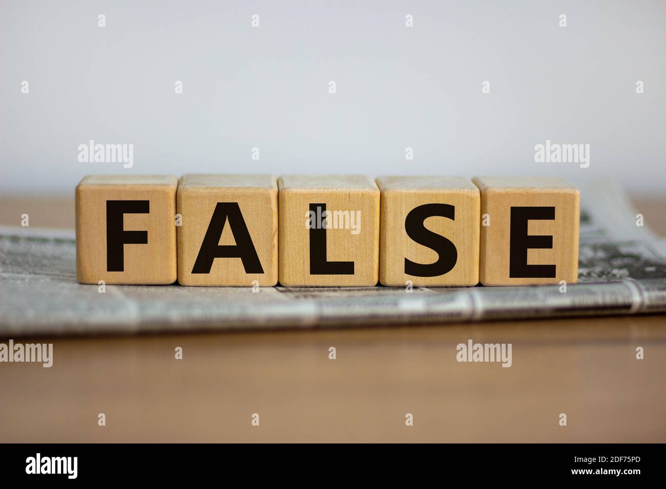 False in news symbol. Cubes placed on a newspaper form the word 'false ...