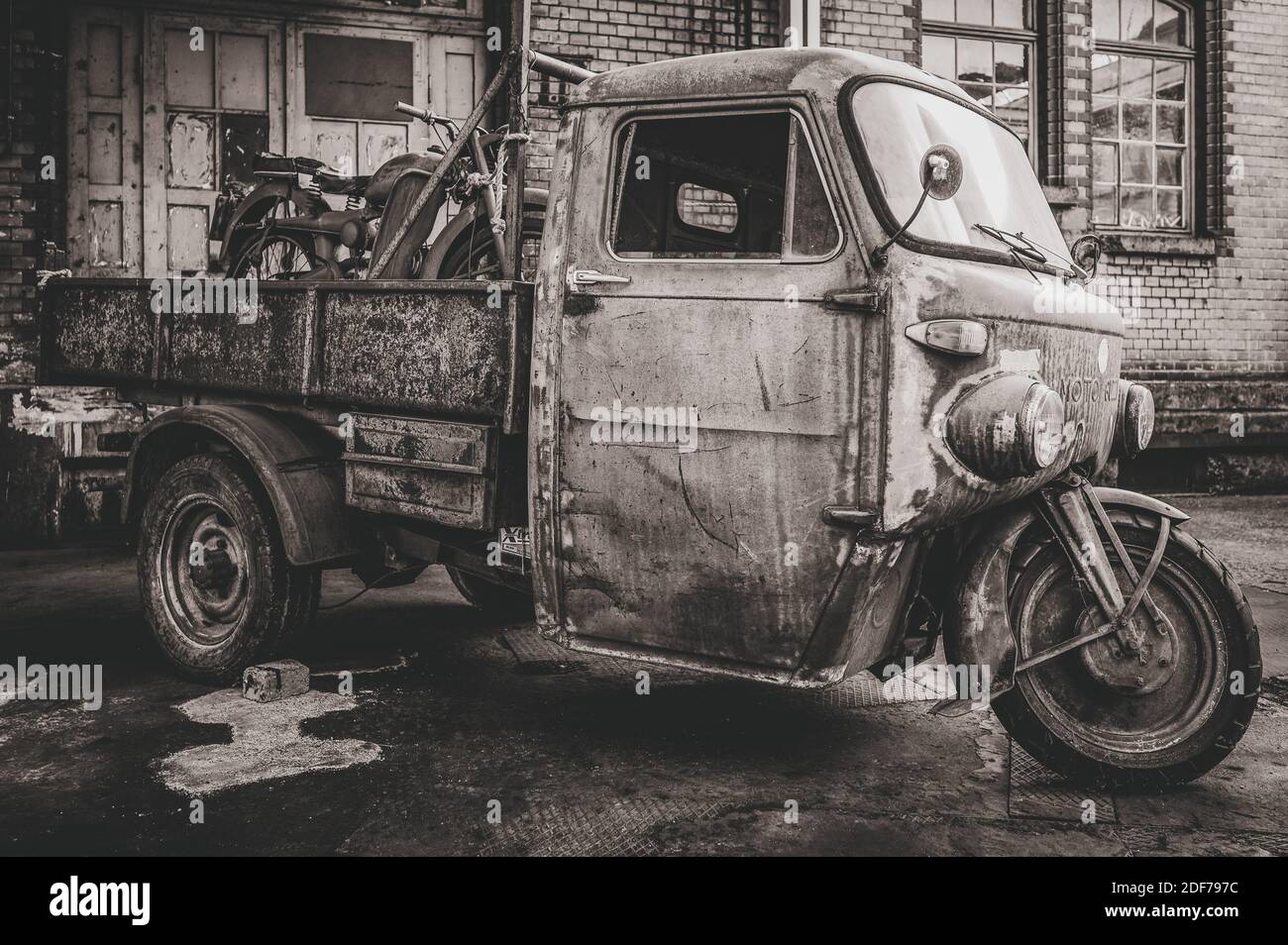 A grayscale shot of a very old truck loaded with old tools and a ...