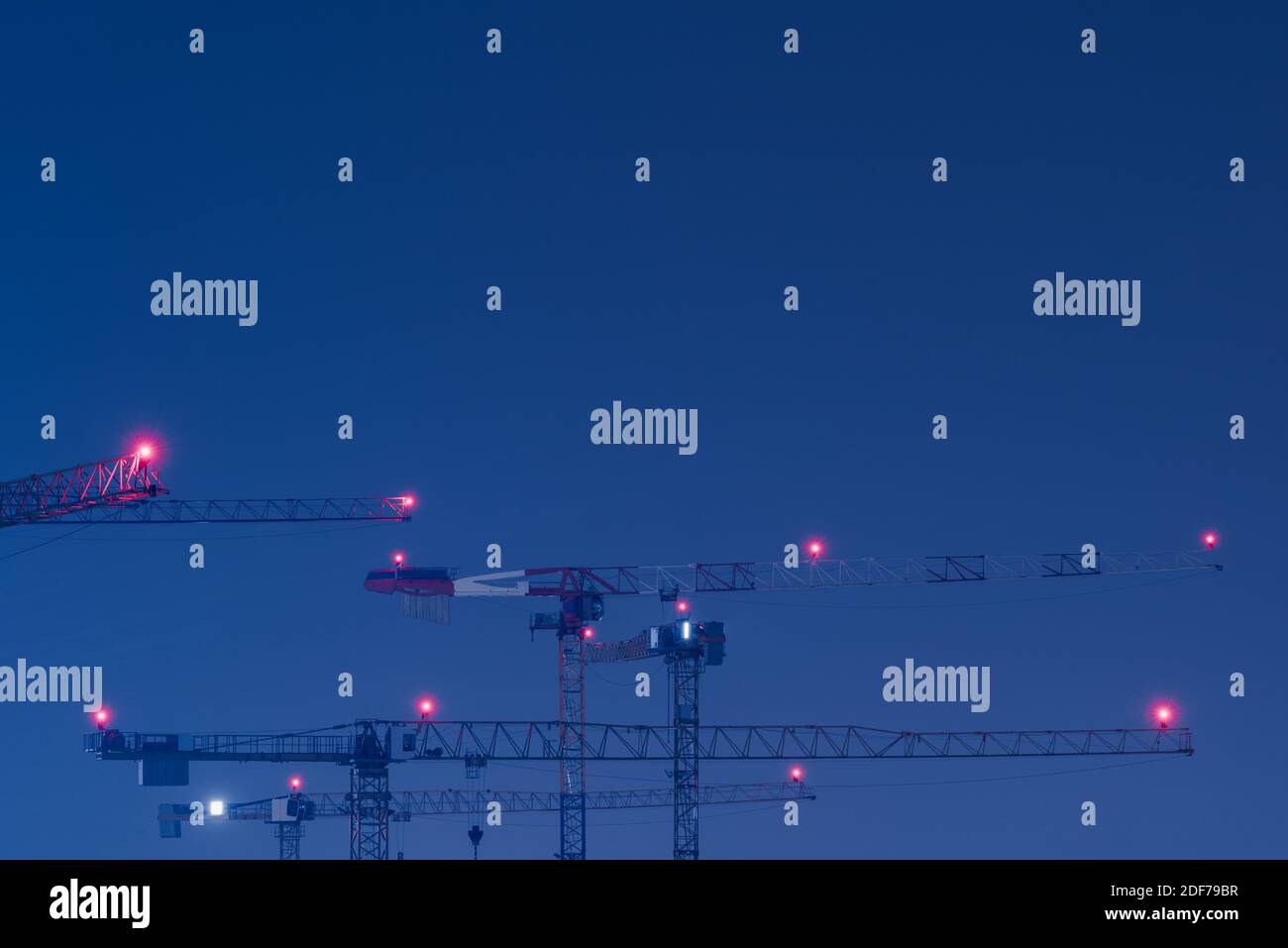 Looking up at group of tall and high tower cranes with red position ...
