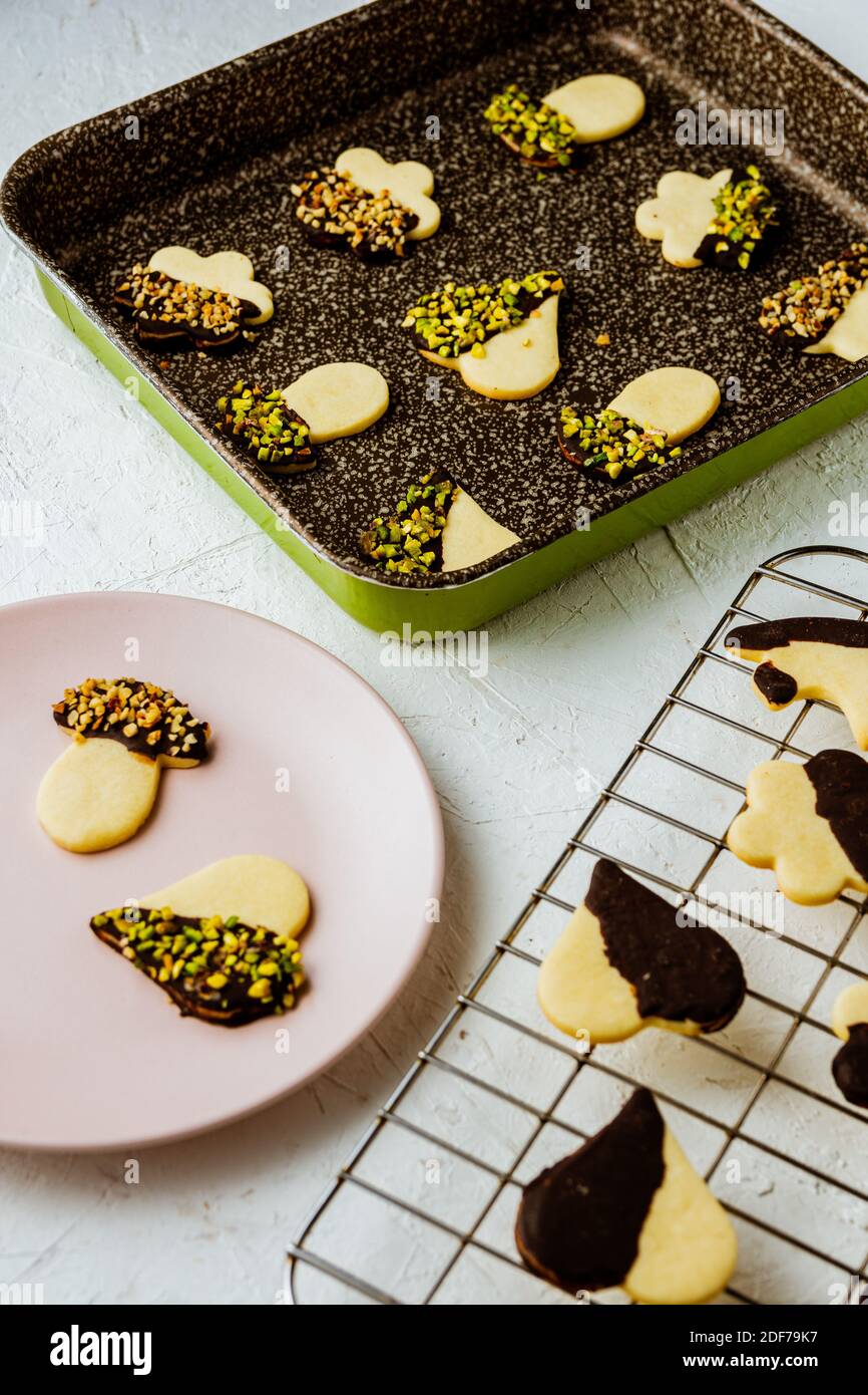 A vertical closeup of cookies on a plate, a pan, and a metallic bar ...