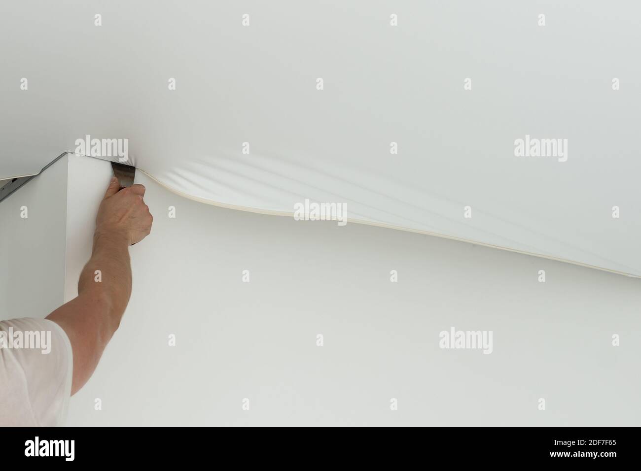 Process of installing stretch ceiling in the hall. Close up of the hand ...