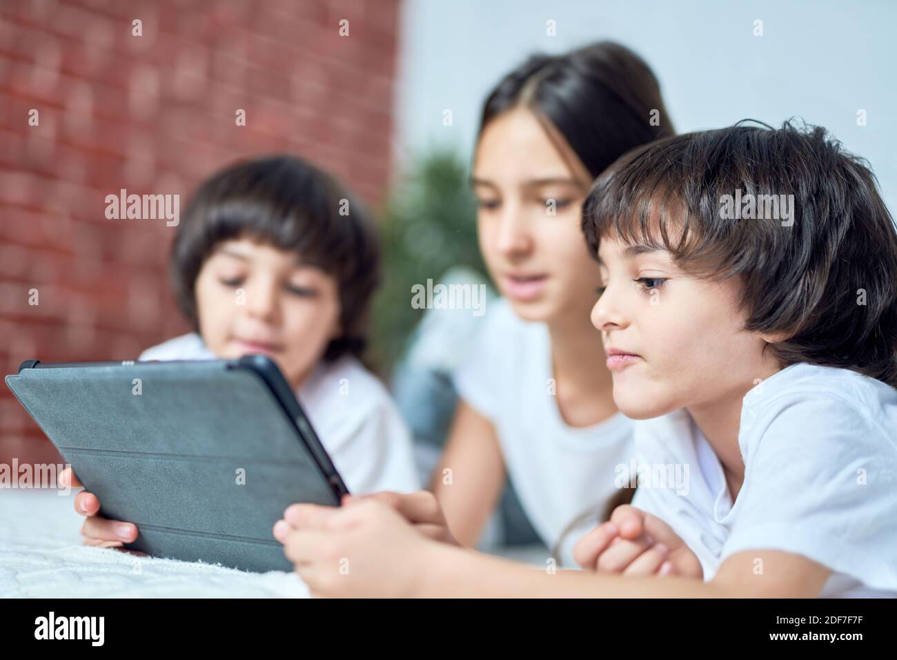 Curious little latin boy looking at the screen of tablet pc. Brother ...