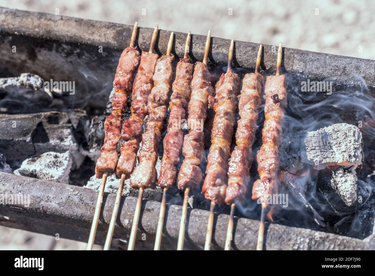 done "Arrosticini" meat smoking on grill, shot in bright light at ...