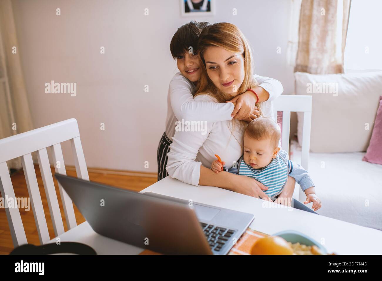 Mother with her baby boy and cute girl working from home Stock Photo ...