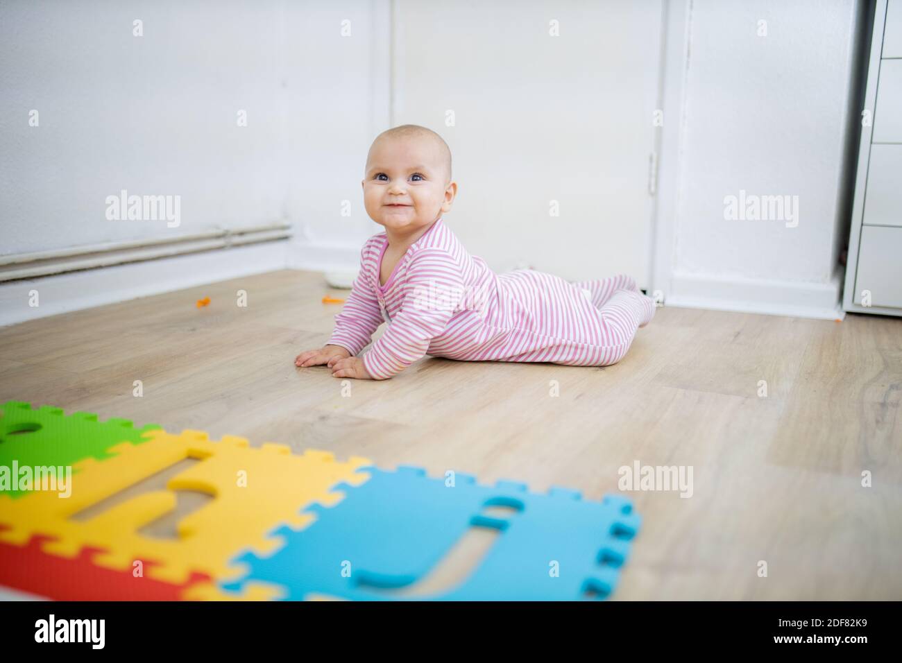 Adorable baby lying face down on the wooden floor Stock Photo - Alamy