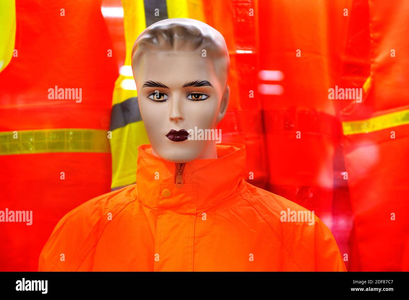 Mannequin in reflective safety orange jacket at window display, in shop ...