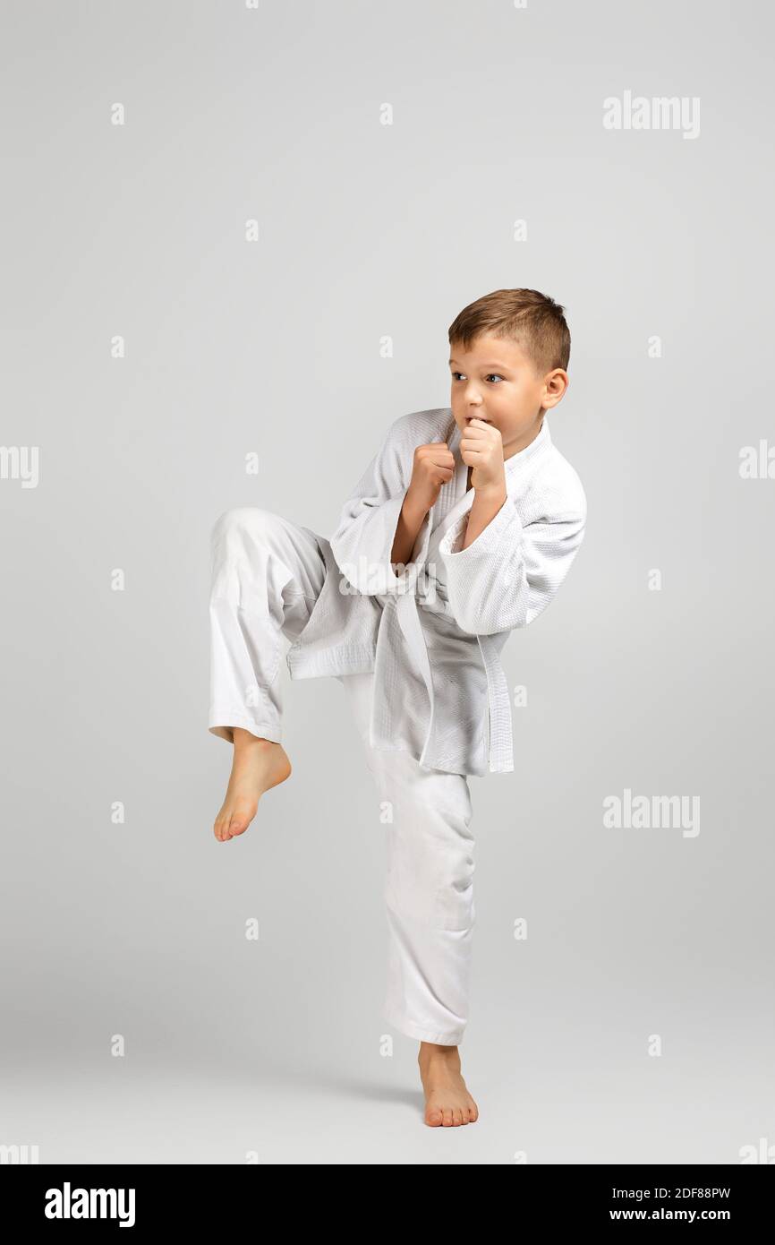little child boy in a white karate kimono training. Full length ...