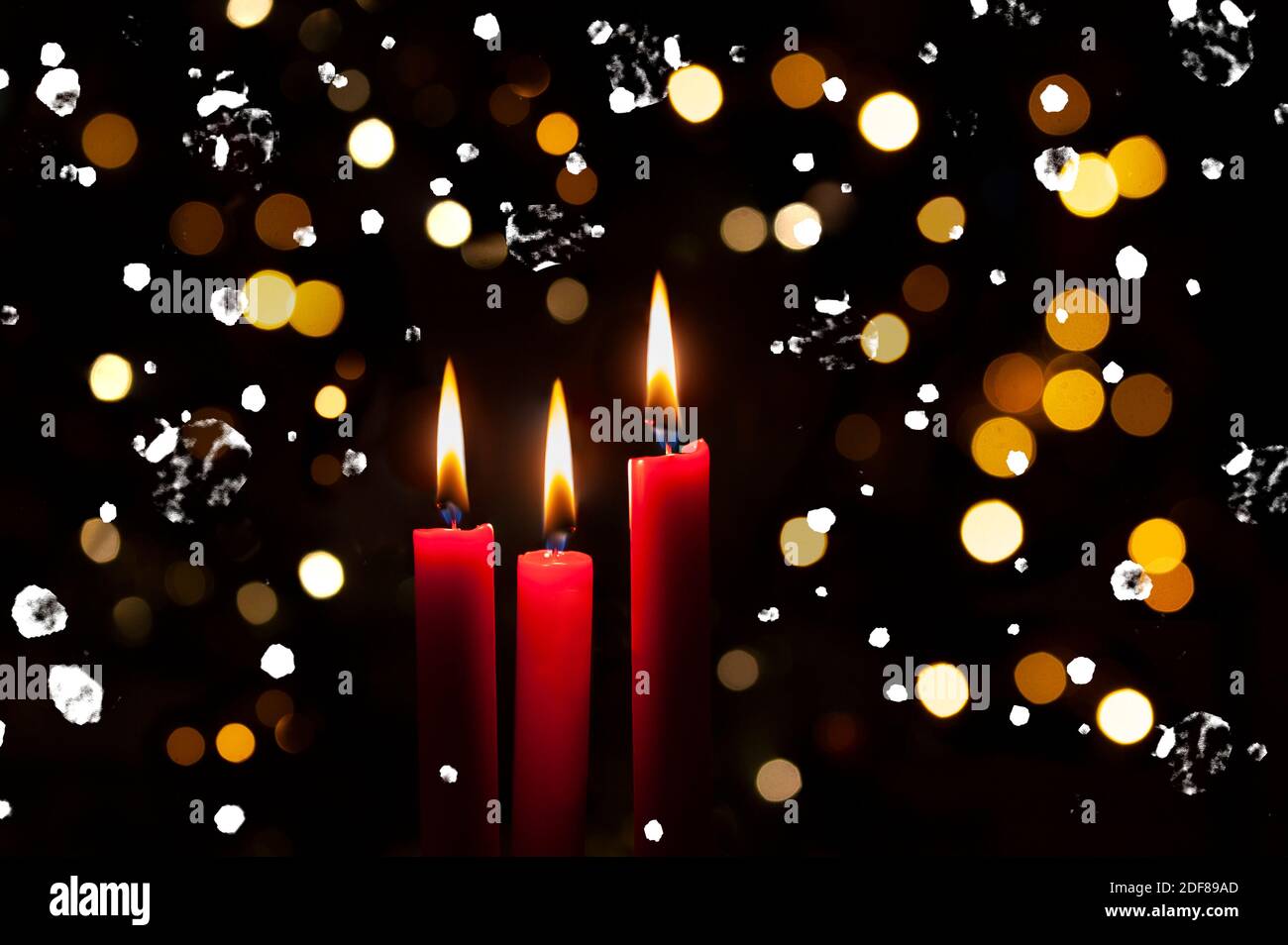 Three red lit candles with colorful bokeh background of spots and snow ...