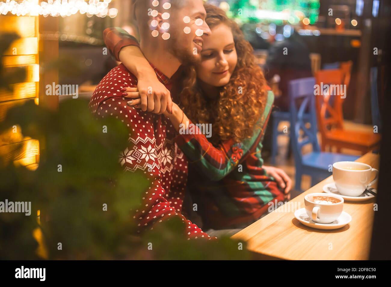 Loving couple in a cafe hug and drink cocoa Stock Photo - Alamy