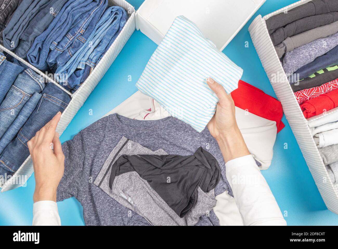 Woman hands folds and puts clothes to baskets. Vertical storage of ...