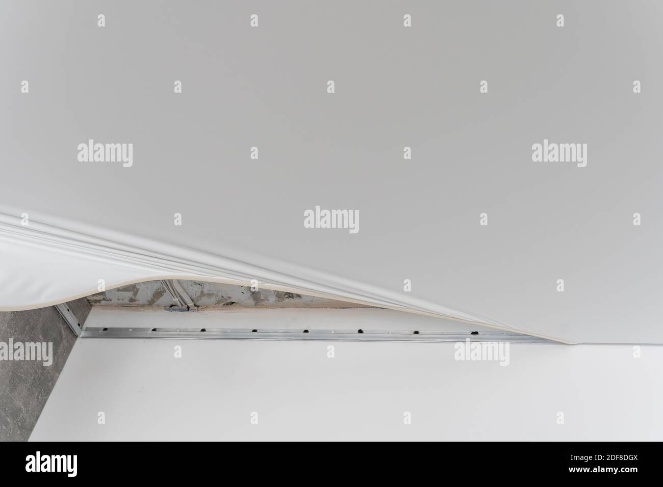 repairmen install stretch ceiling made of pvc vinyl film using a gas ...